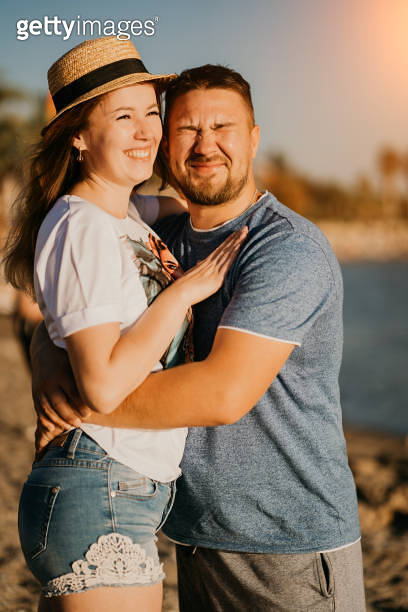 bright sun. a man and a woman in love squinting from the sun hug on the ...