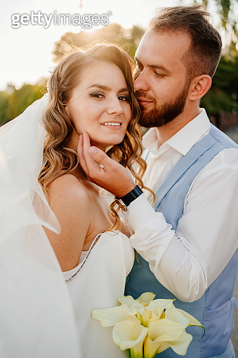 solar glare. bride with long curls in a white elegant dress with a ...