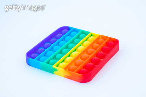 Colorful rainbow poppit game. Silicone fidget close-up on a white ...