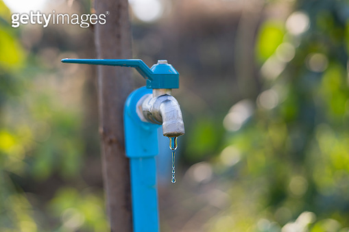 Faucet flowing open water tap with drop water in the park green bokeh ...