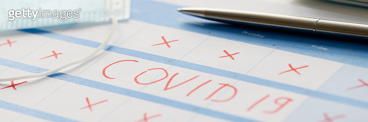 Pen lying on table with calendar with red strikethrough dates during ...