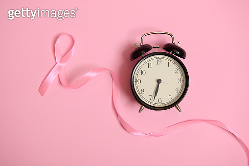 Long pink satin ribbon, where one end is endless and alarm clock on ...