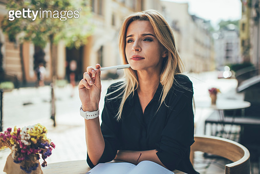 Thoughtful female poet pondering on idea for creating article holding ...