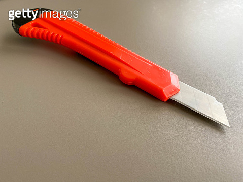 Red sharp office stationery knife with a paper cutting blade on a ...
