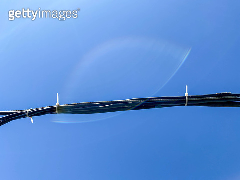 Thick black electrical industrial high voltage wire cable on a blue sky ...