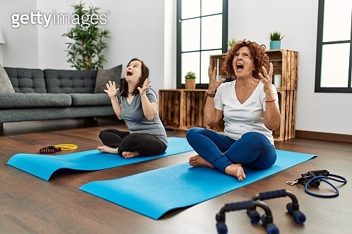 Family of mother and down syndrome daughter doing exercise at home ...