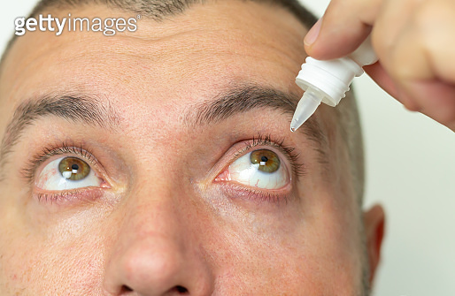 Man applying liquid eye drops in his eye solving vision problem close ...