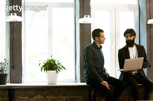 Young men working in modern office using devices and gadgets. Making ...