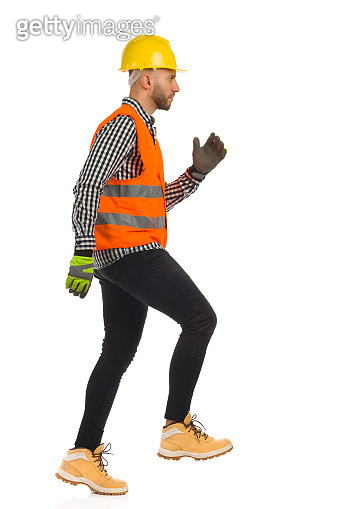 Construction worker is going up the stairs. Side view. Studio shot ...