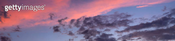 Dark and glowing red clouds clouds on a blue sky at sunset.Dark red ...