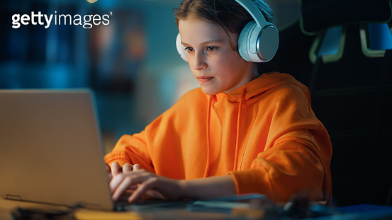 Smart Young Boy in Headphones Using Laptop Computer in a Dark Cozy Room ...