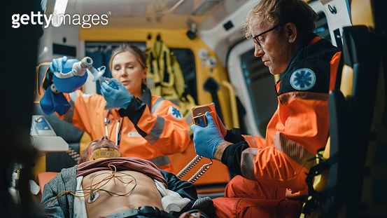 Female and Male EMS Paramedics Provide Medical Help to an Injured ...
