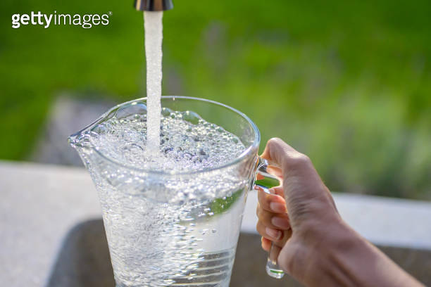 Filling glass pitcher with fresh water from tap (1307942813) - 게티이미지뱅크
