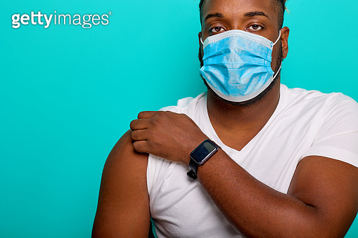 African-American man in an antiviral mask pulled up the sleeve of a ...