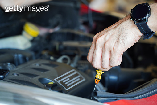 Auto mechanic checking the oil level in car engine,inspects engine ...