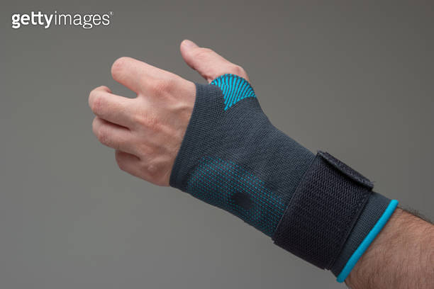 Velcro wrist stabilizer cast worn by Caucasian male hand. A blue split ...