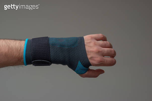 Velcro wrist stabilizer cast worn by Caucasian male hand. A blue split ...