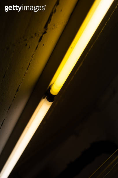 Old defective flickering yellow neon lights ceiling mounted inside dark ...