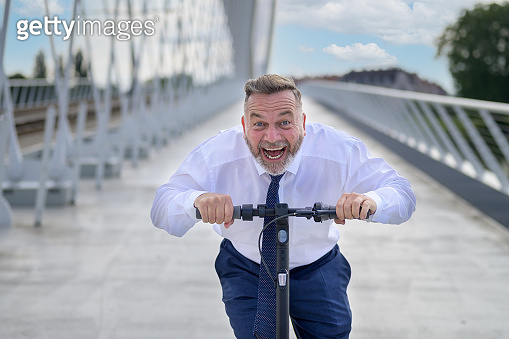 Gleeful laughing man speeding along on an electric scooter 이미지 ...