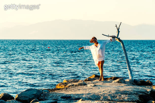 Single woman at the beach, posing next to a tree 이미지 (1314131168) - 게티이미지뱅크