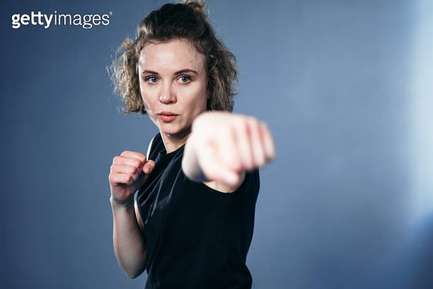 Female fighter throws punches directly into camera. Woman athlete ...