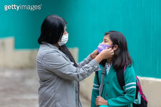 Mexican mother and daughter wearing protective face mask on back to ...