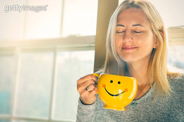 Woman Smelling Coffee in Smiley Face Mug 이미지 (1352330530) - 게티이미지뱅크