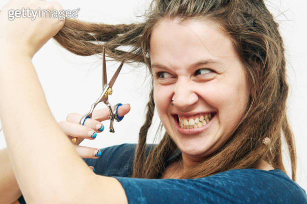 Young woman with messy, tangled long hair gets ready to cut it with ...