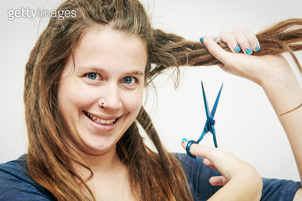 Young woman with messy, tangled long hair gets ready to cut it with ...
