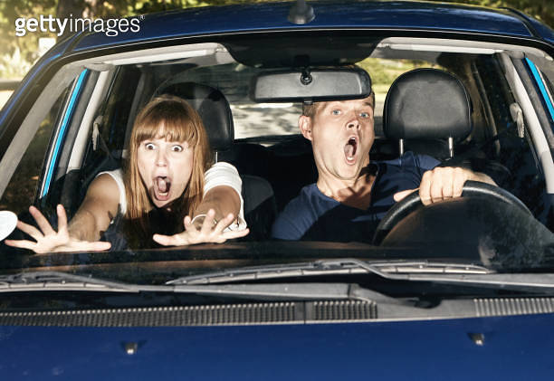 Young couple react to danger with shock and horror as they drive in a ...