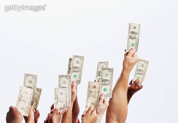 Many people hold up US dollar banknotes of various denominations ...