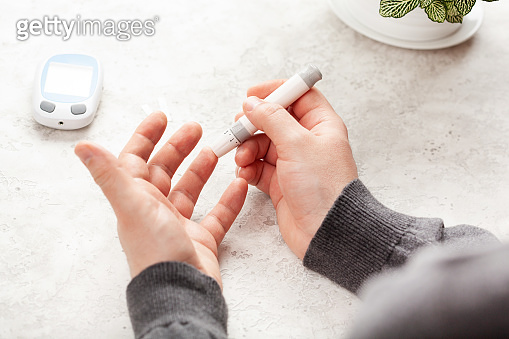 man hands using lancet on finger to check blood sugar or ketones level ...
