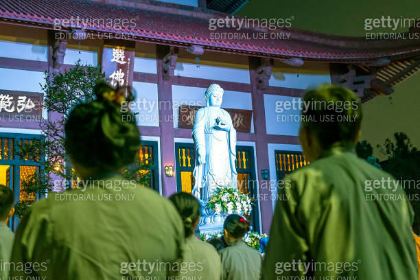 Monks and Buddhists are reverently bowing to Buddha during evening ...