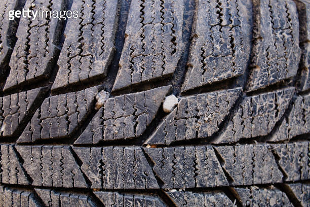 Close-up of grooves on a car tire, stones stuck inside the rubber ...