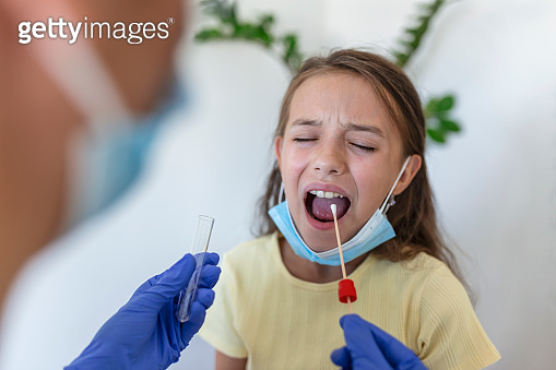 Nurse performing a mouth swab test on a little child. Girl going ...