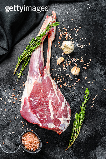 Raw goat leg with salt and garlic. Farm meat. Black background. Top ...