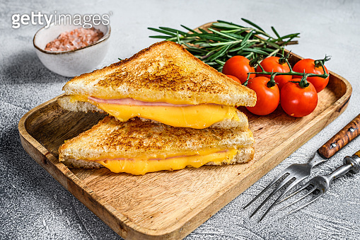 Homemade fried ham and cheese sandwich on a cutting board. White ...