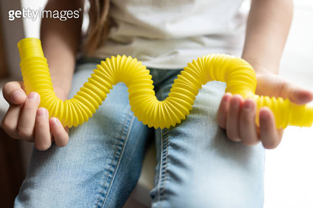 anti stress sensory pop tube plastic toy in a kid's hands. a little ...