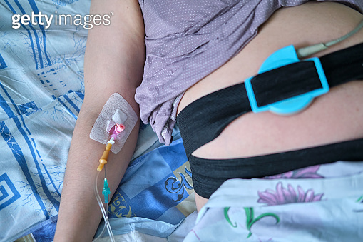 A pregnant woman gives birth in a hospital with a drip and a ...