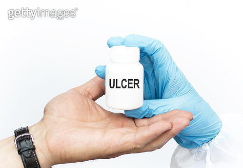 The doctor's gloved hand passes the bottle with the name of the ...