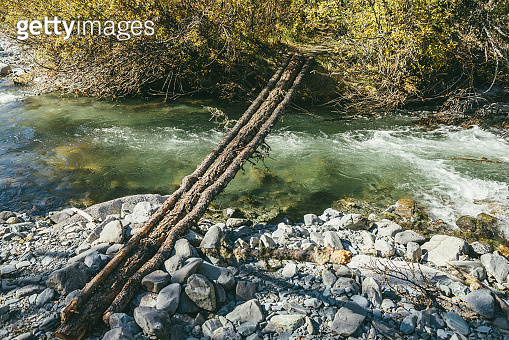 Scenic landscape with log bridge over mountain river in wild autumn ...