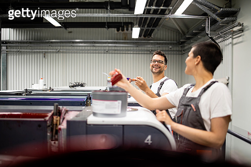 Printing machine operators working with ink paint together in print ...