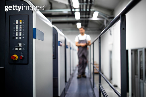 Close up view of modern offset printing press machine and operator in ...