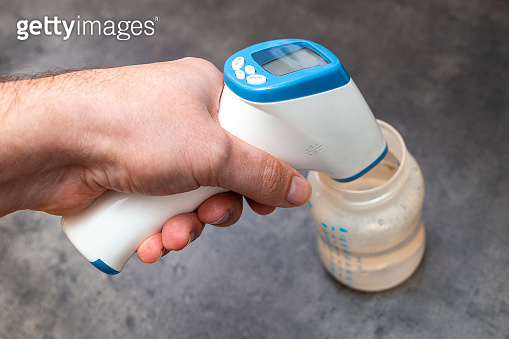 Close up view of measuring water temperature for infants. Preparation ...