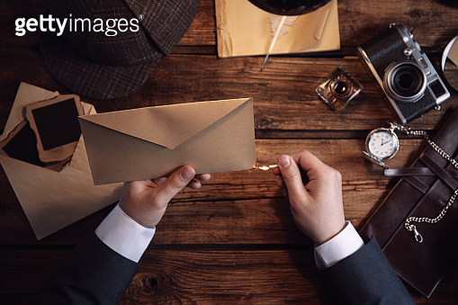 Detective set envelope on fire with match at wooden table, top view ...