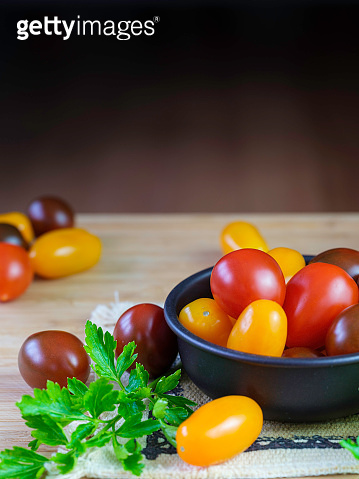 Vibrant Colored Grape Tomatoes in a Brown Bowl and Green Parsley Leaves ...