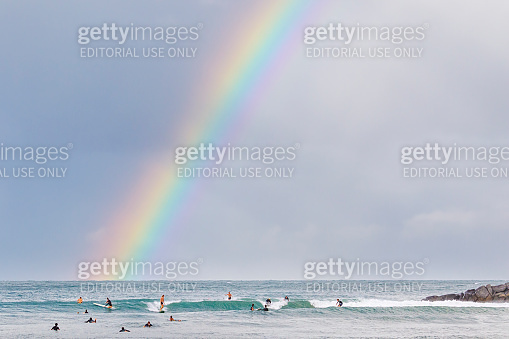 People are surfing at Tea Tree Bay in Noosa National Park under a ...
