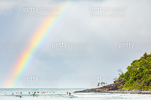 People are surfing at Tea Tree Bay in Noosa National Park under a ...