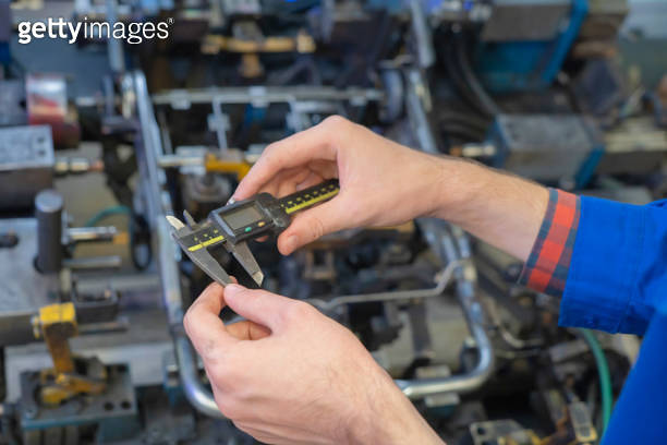 Industrial worker on quality control using steel measuring tape measure ...