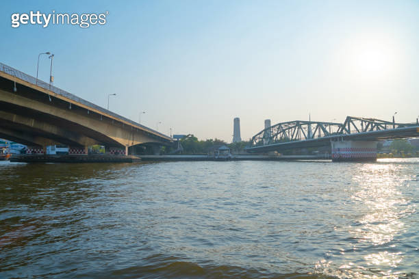 Memorial Bridge, and Phra Pok Klao Bridge with buildings and Chao Phraya River at noon. Urban ...